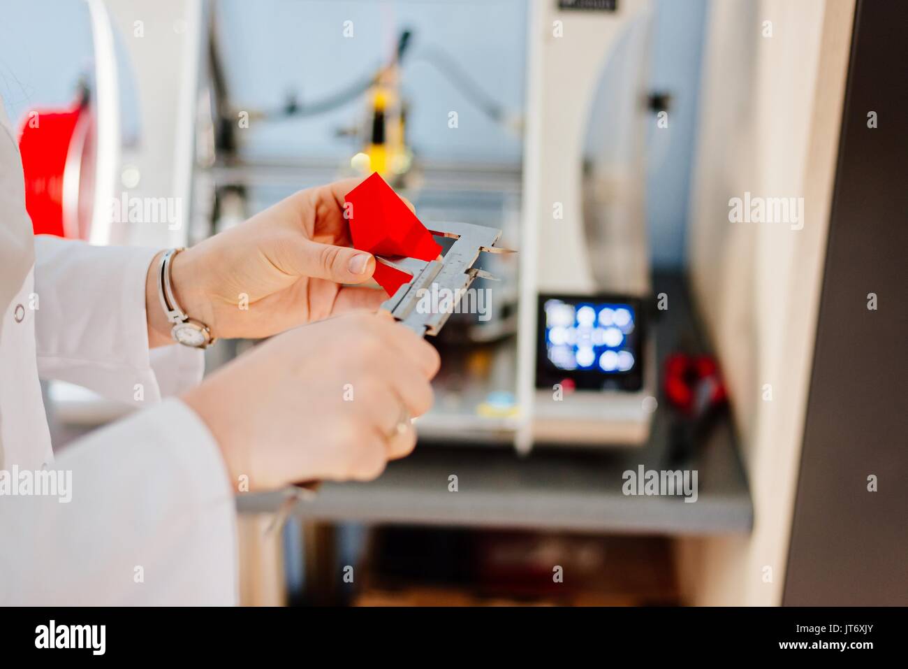 Woman checking the dimensions of the component made in the 3d printer ...