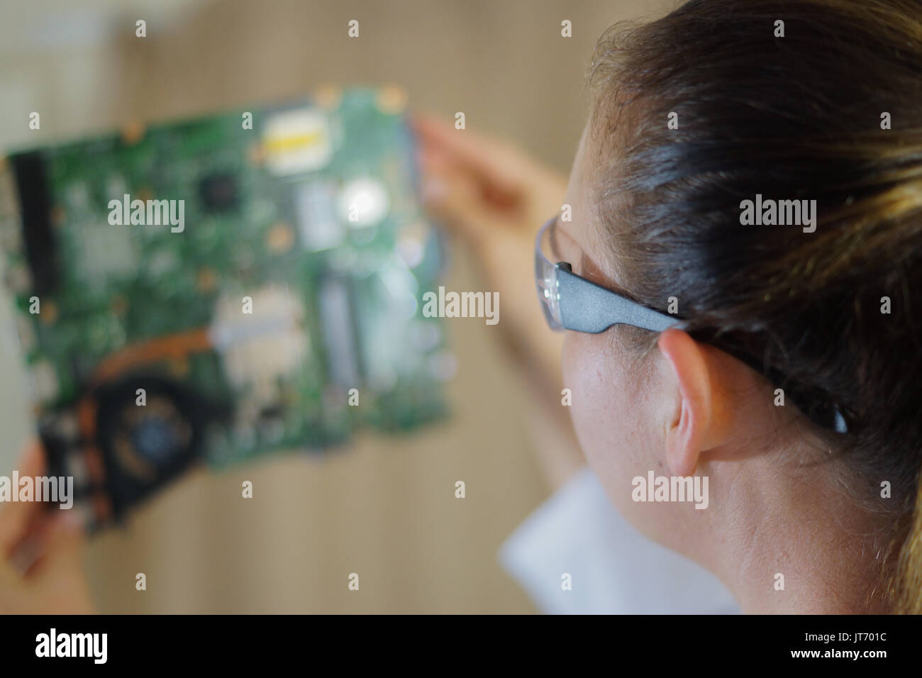 A female computer engineer examines and works on a motherboard Stock ...