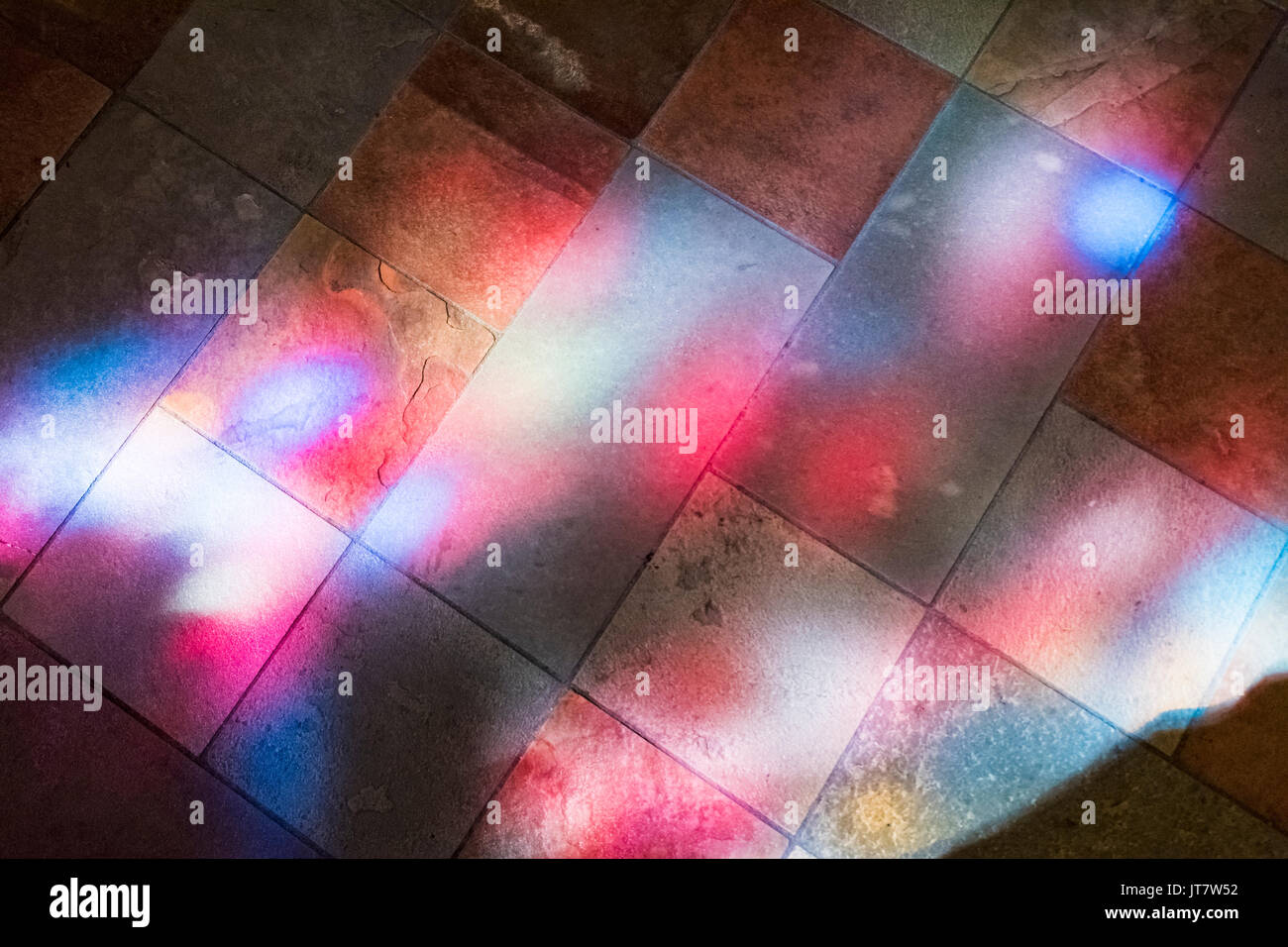 Colorful reflections of stained glass murals on stone ground closeup ...