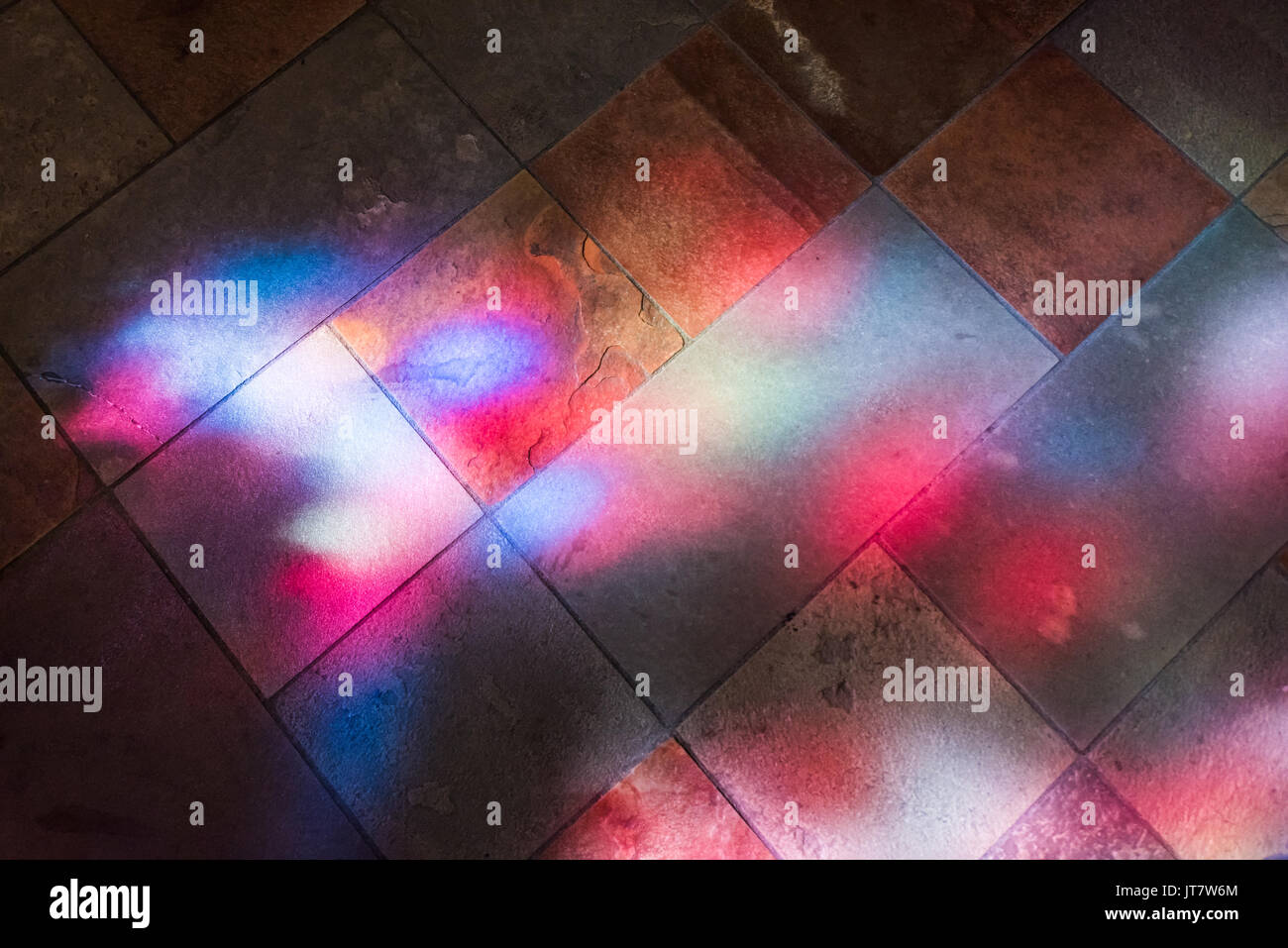 Colorful reflections of stained glass murals on stone ground closeup ...