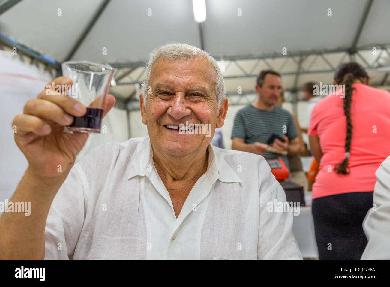Senior man making a toast at the food stand of a country village ...