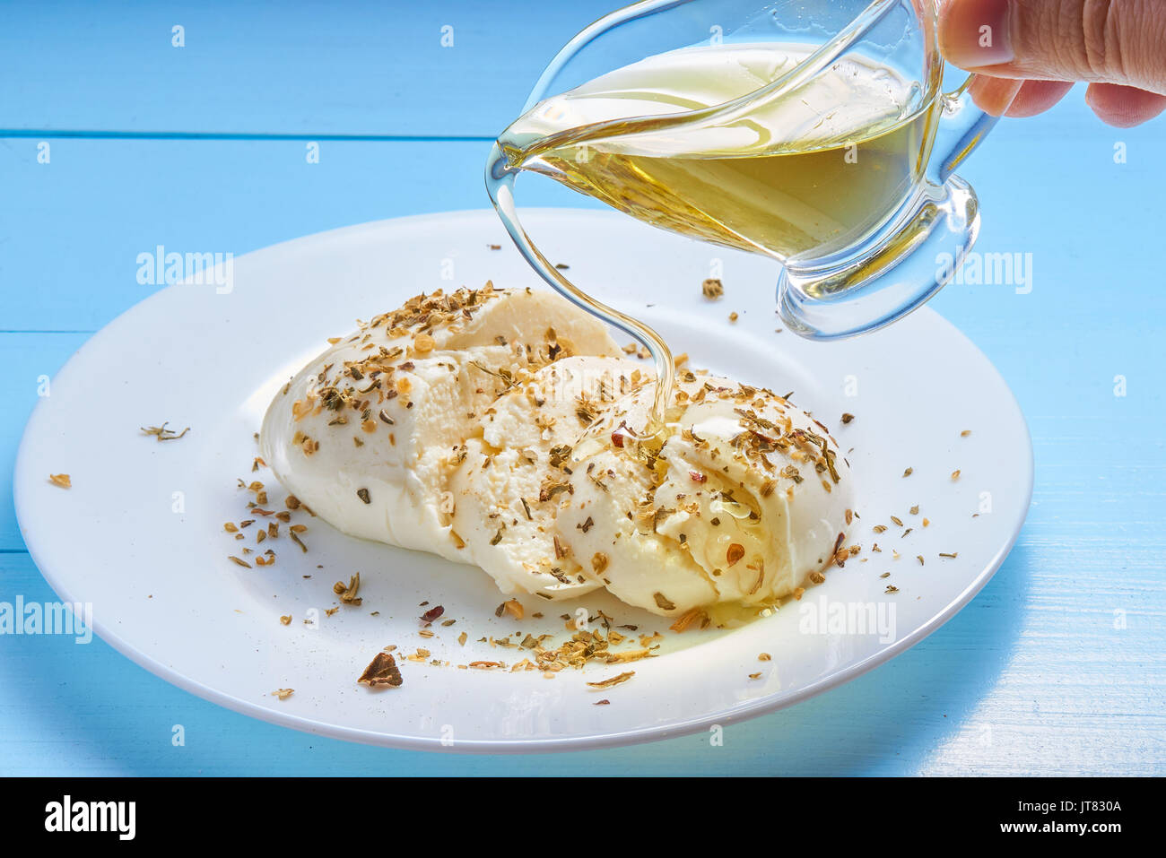 closeup of olive oil pouring on mozzarella cheese. detailed shot on ...