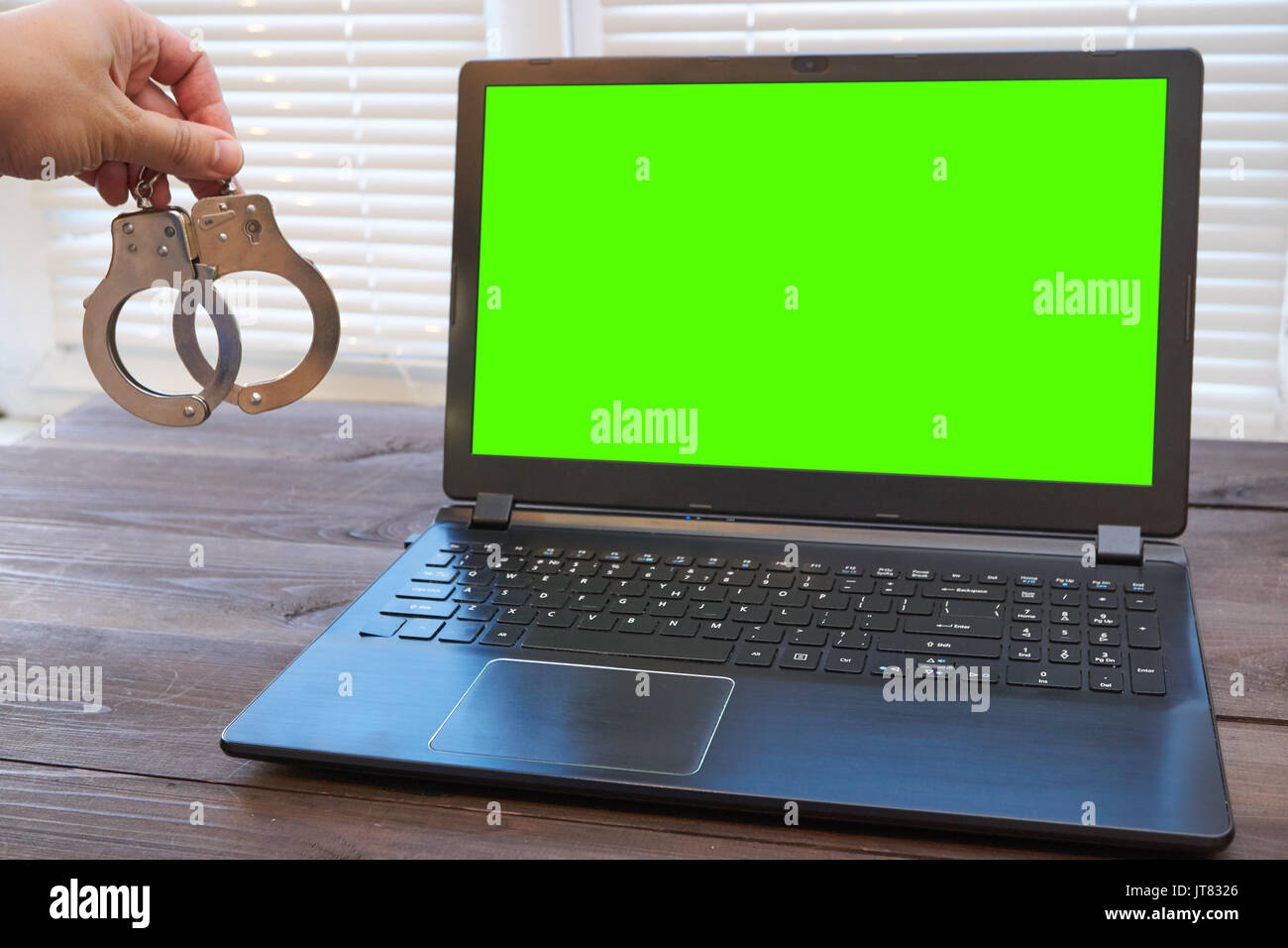 man holding handcuffs near laptop with green screen. concept image of ...