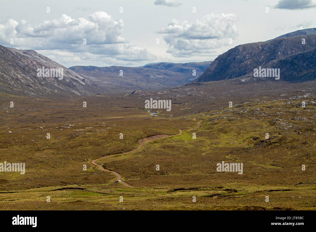 Vast landscape in Scottish highlands with narrow road snaking through ...