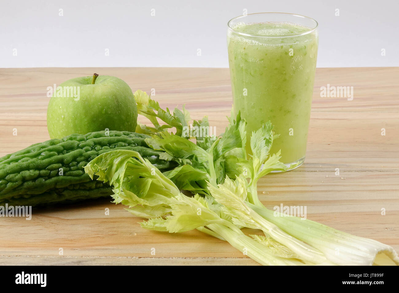 Green apple, bitter gout and celery isolated on wooden background to ...