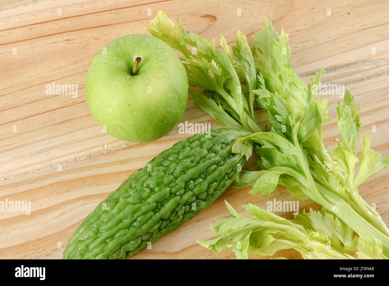Green apple, bitter gout and celery isolated on wooden background to ...