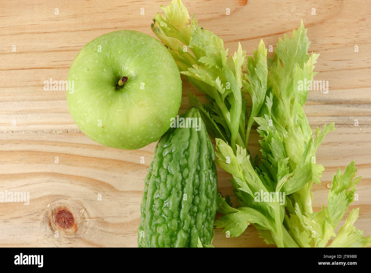 Green apple, bitter gout and celery isolated on wooden background to ...