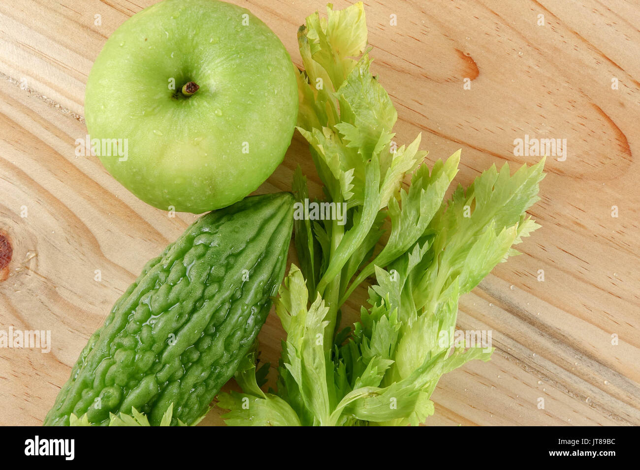 Green apple, bitter gout and celery isolated on wooden background to ...