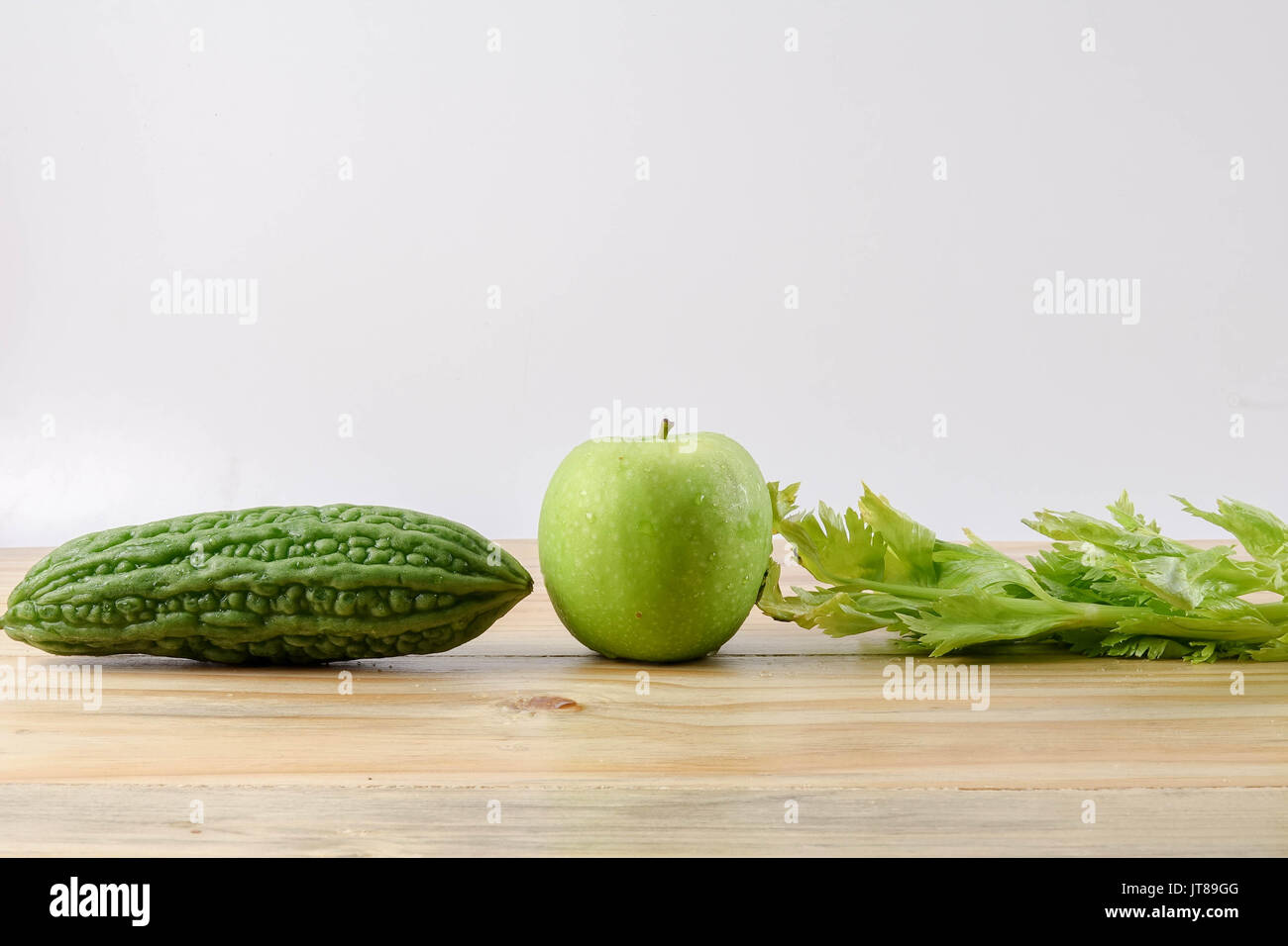Green apple, bitter gout and celery isolated on wooden background to ...