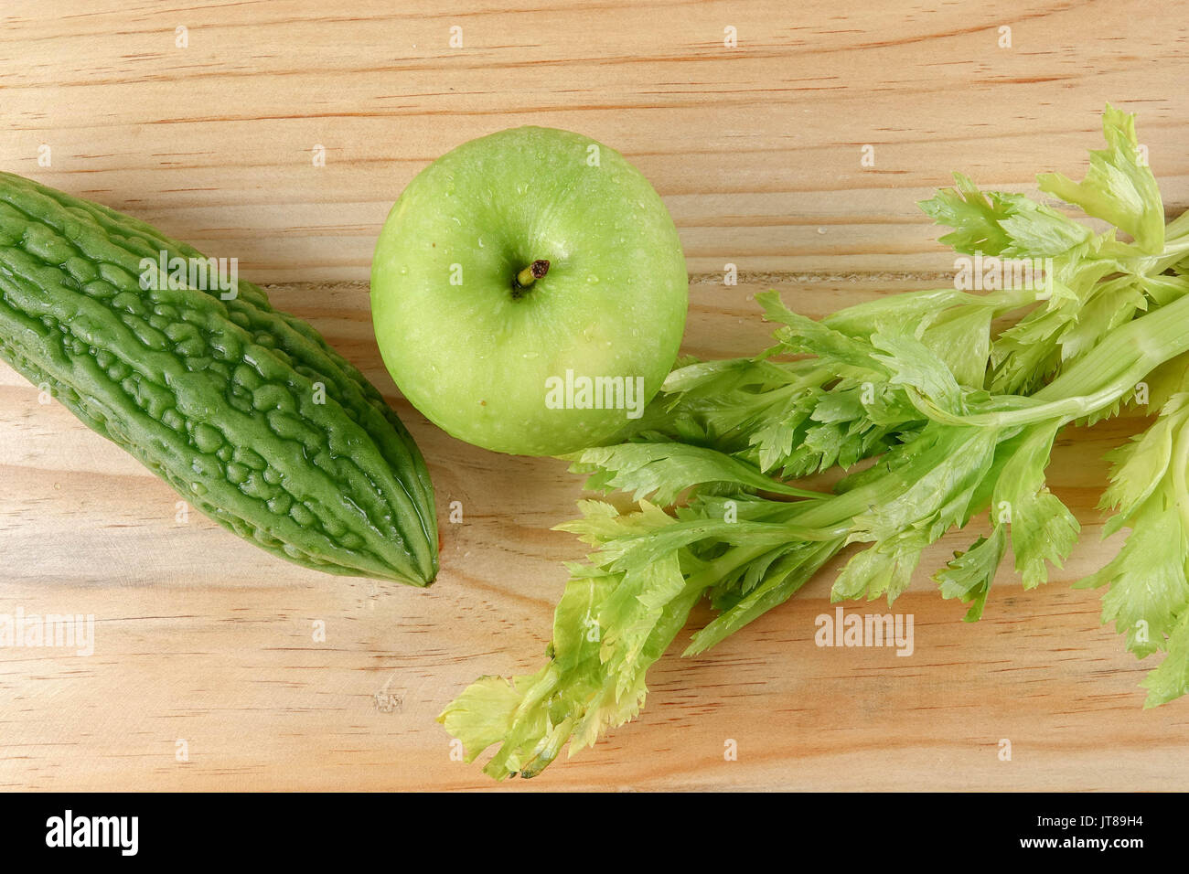 Green apple, bitter gout and celery isolated on wooden background to ...