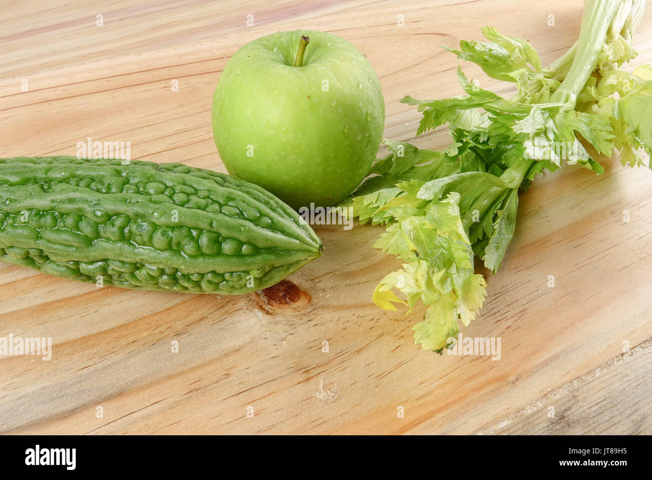 Green apple, bitter gout and celery isolated on wooden background to ...