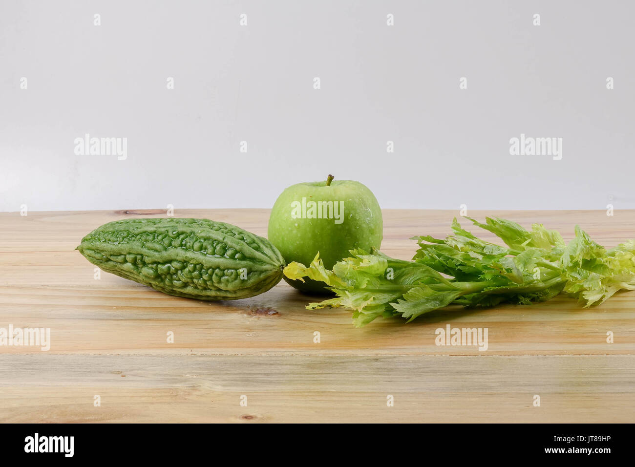 Green apple, bitter gout and celery isolated on wooden background to ...