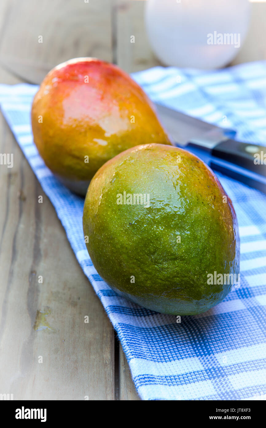 Fresh ripe raw mangos on a rustic wood table top in Southern California ...