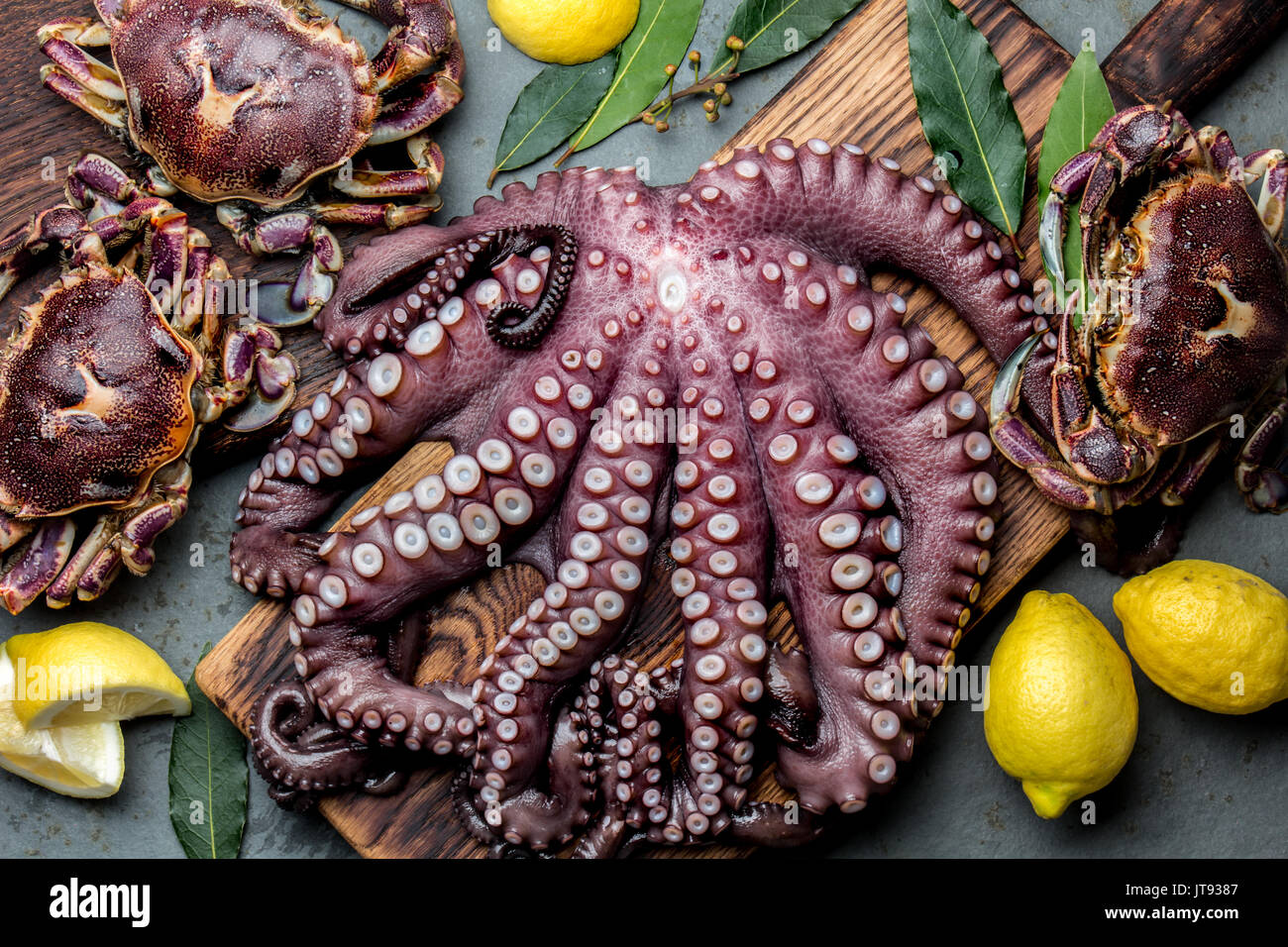 Seafood octopus. Whole fresh raw octopus and crabs on wooden board with ...