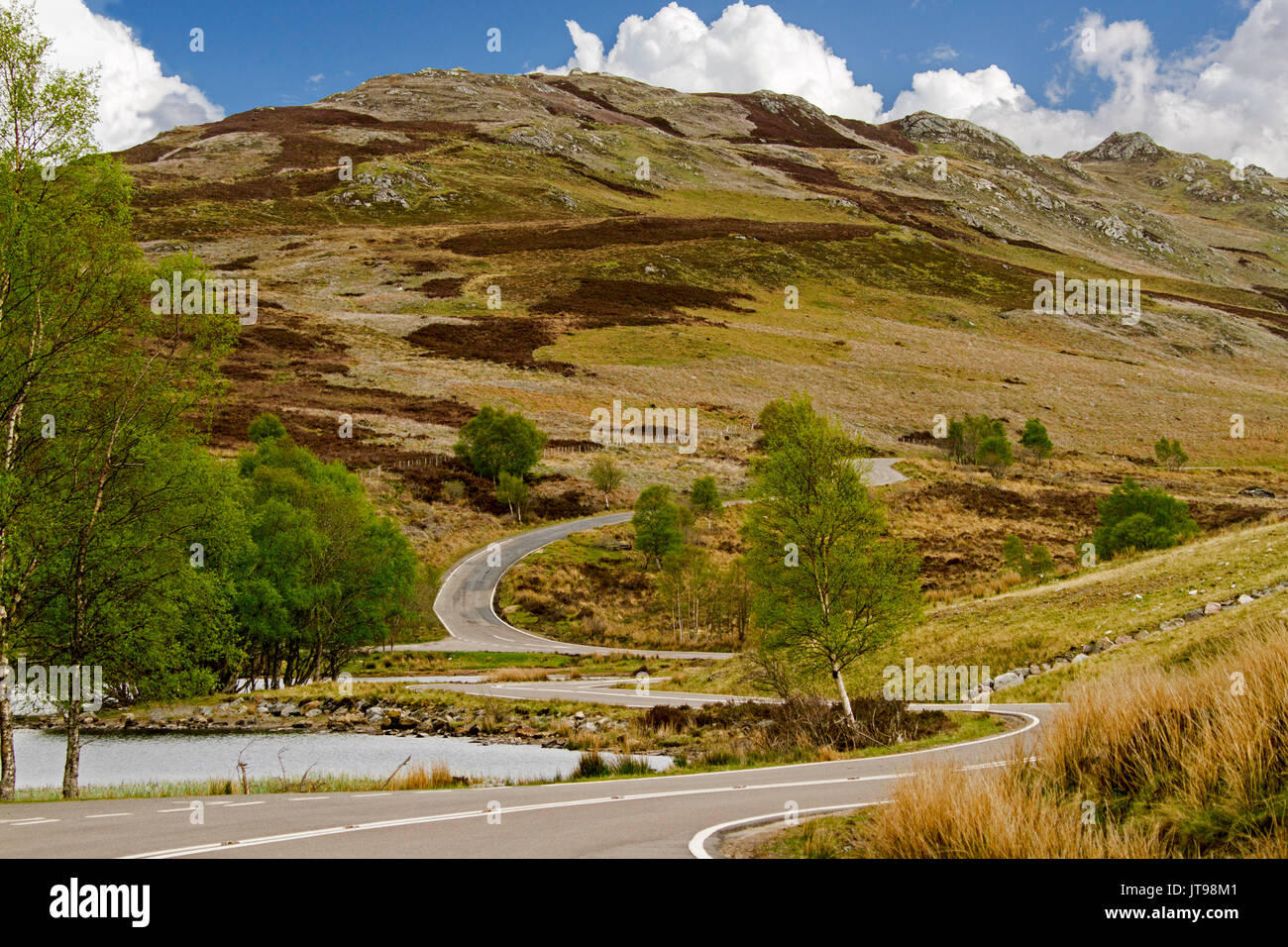 Road winding through rugged & mountainous Scottish highland landscape ...