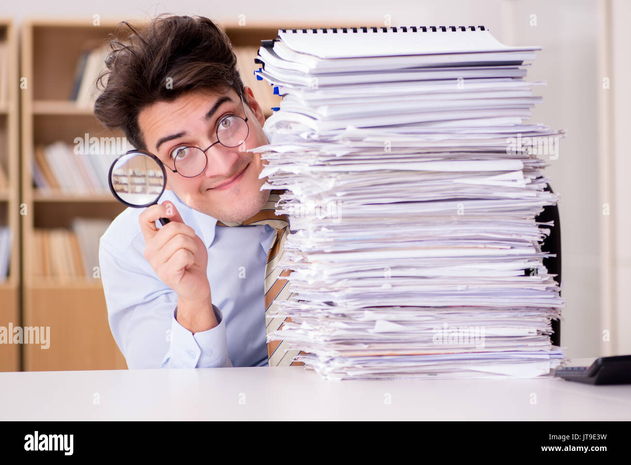 Funny auditor checking reports with magnifying glass Stock Photo - Alamy