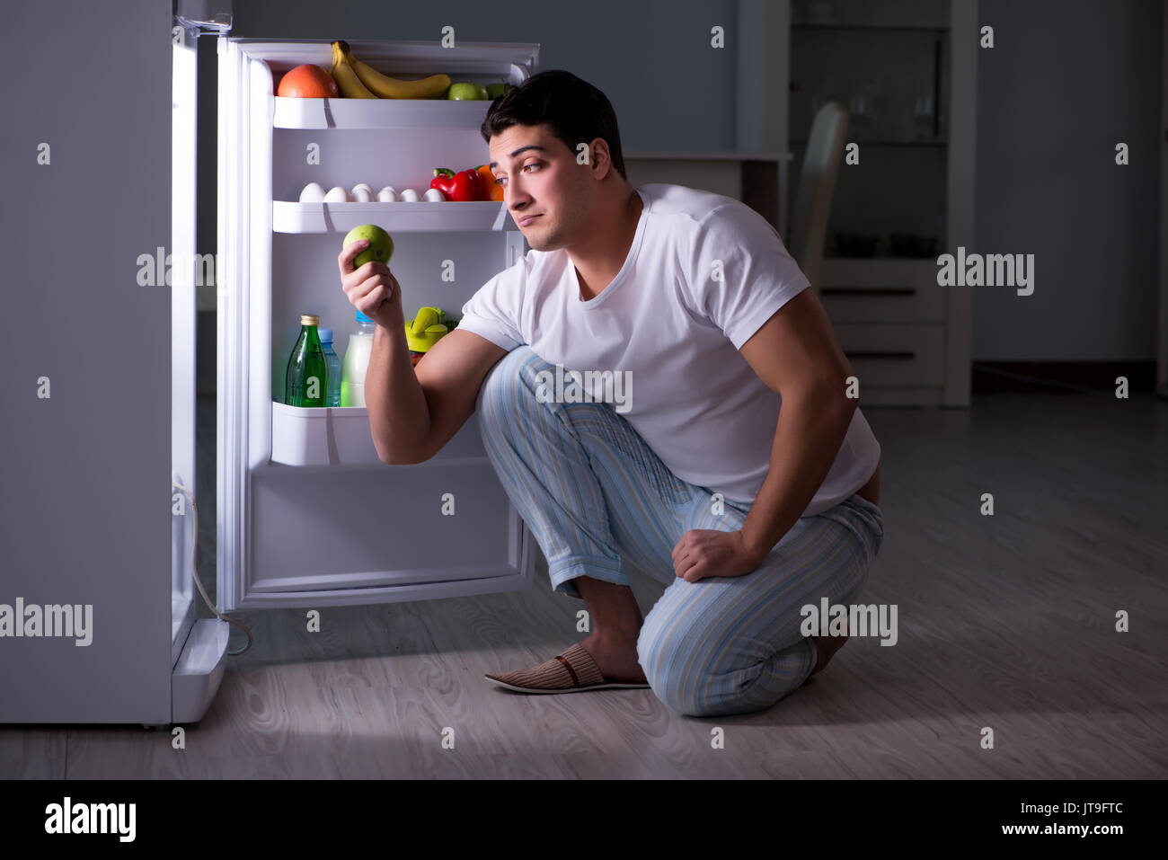Man at the fridge eating at night Stock Photo - Alamy