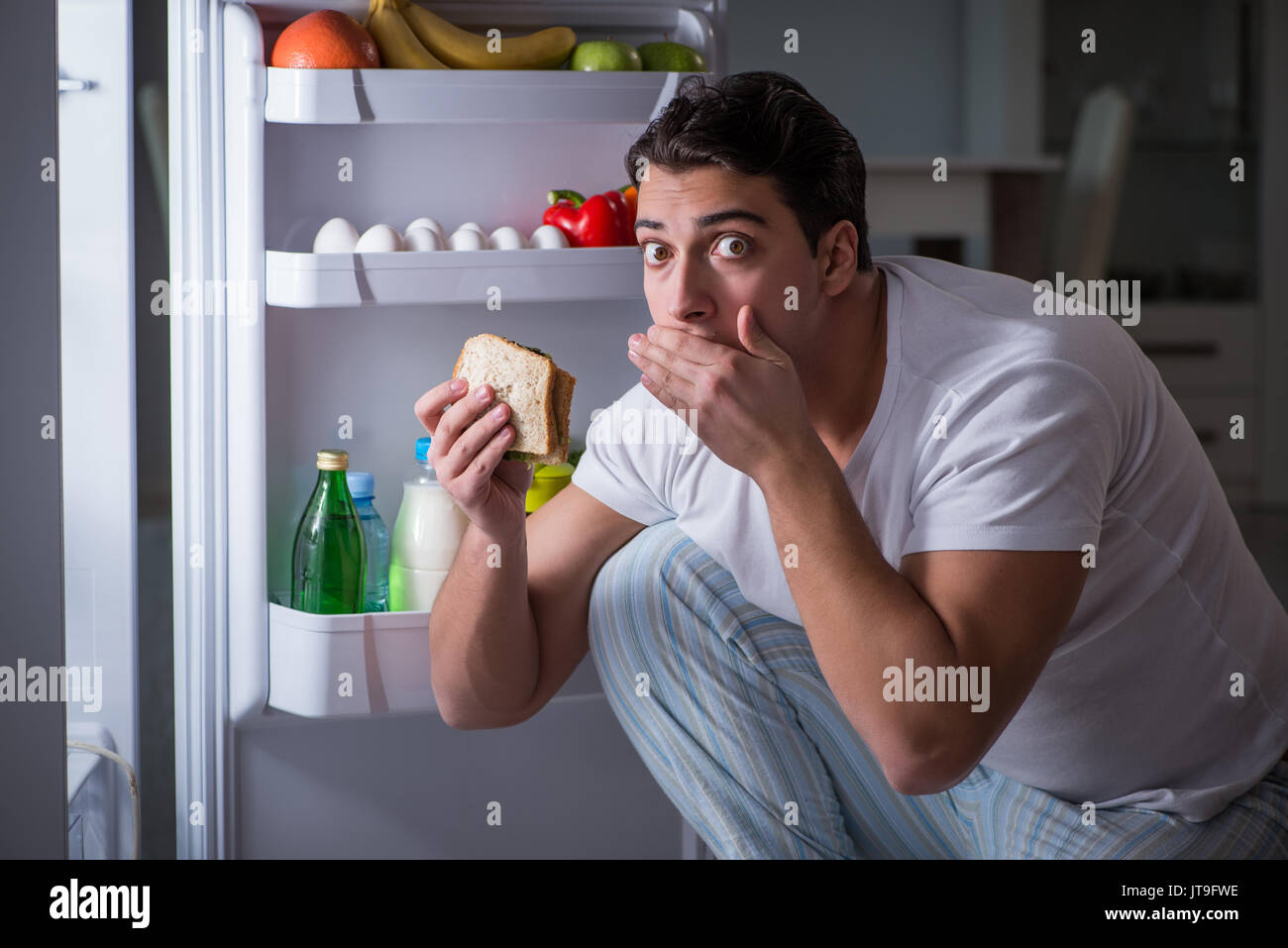 Man at the fridge eating at night Stock Photo - Alamy
