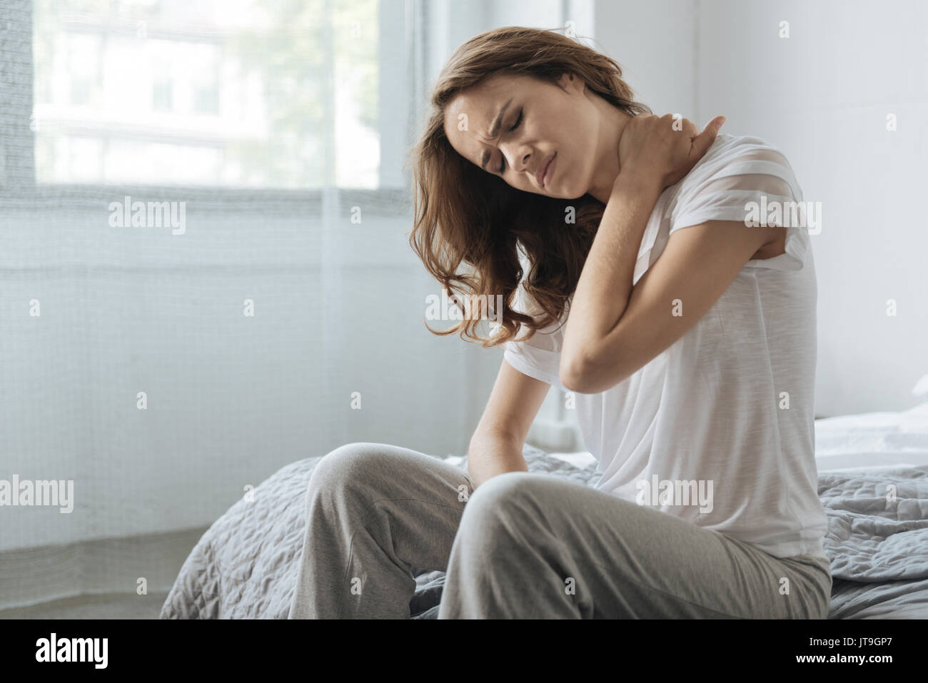 Moody young woman holding her neck Stock Photo - Alamy