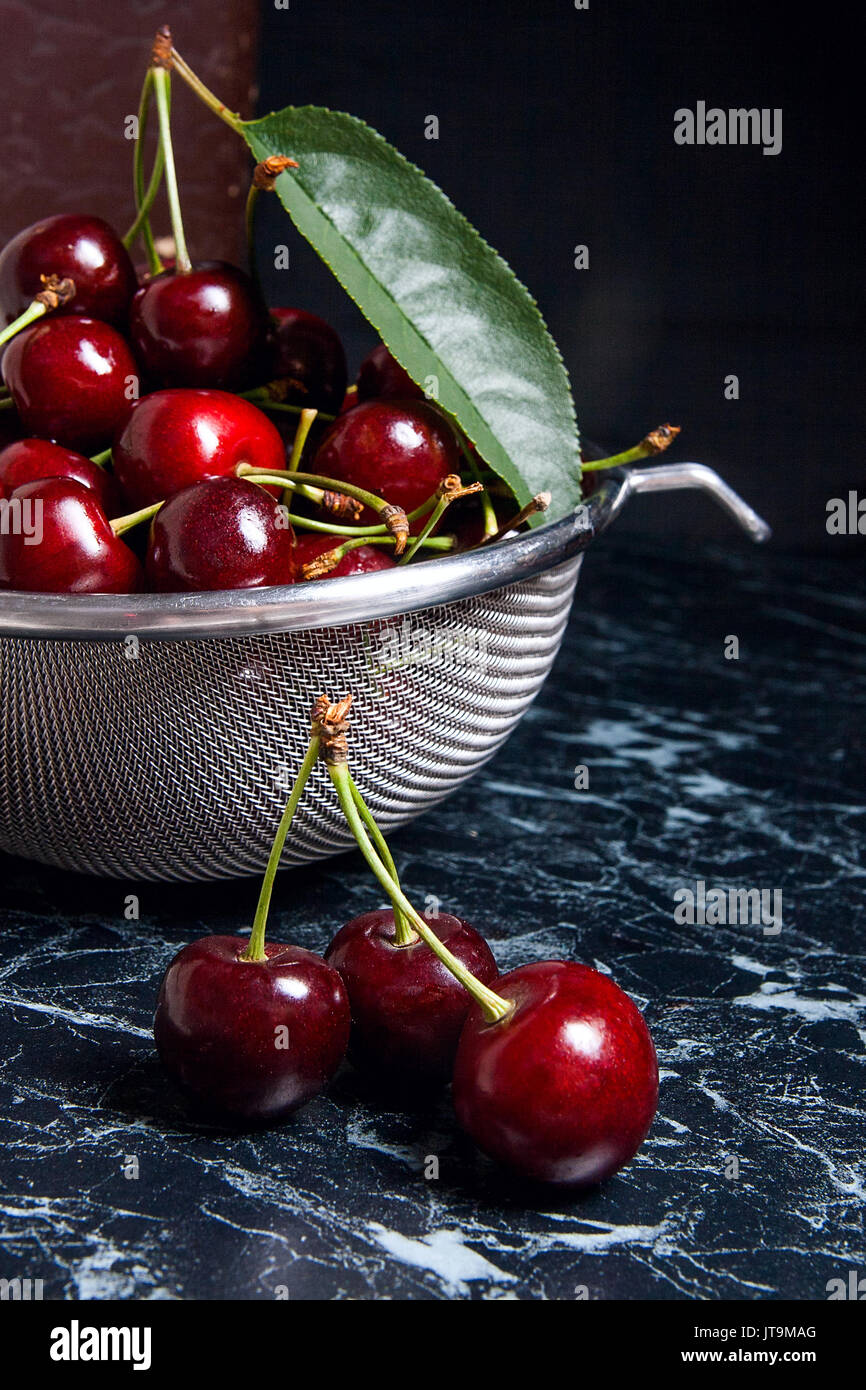 Close up view of several red sweet cherries and big green leaf of ...