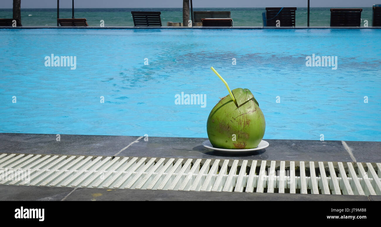 Fresh coconut juice with a drinking straw by the swimming pool Stock ...