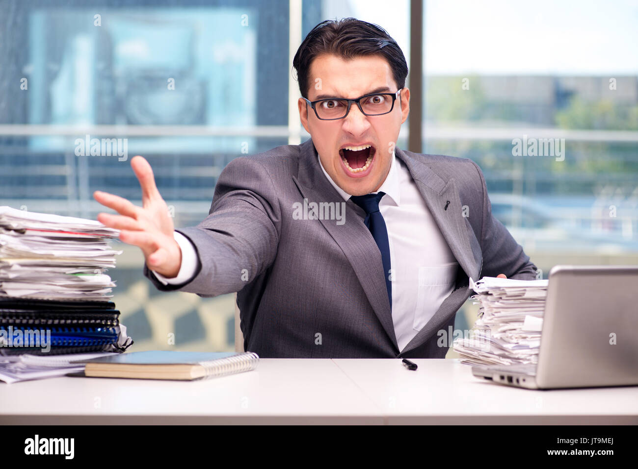Angry businessman with too much work in office Stock Photo - Alamy
