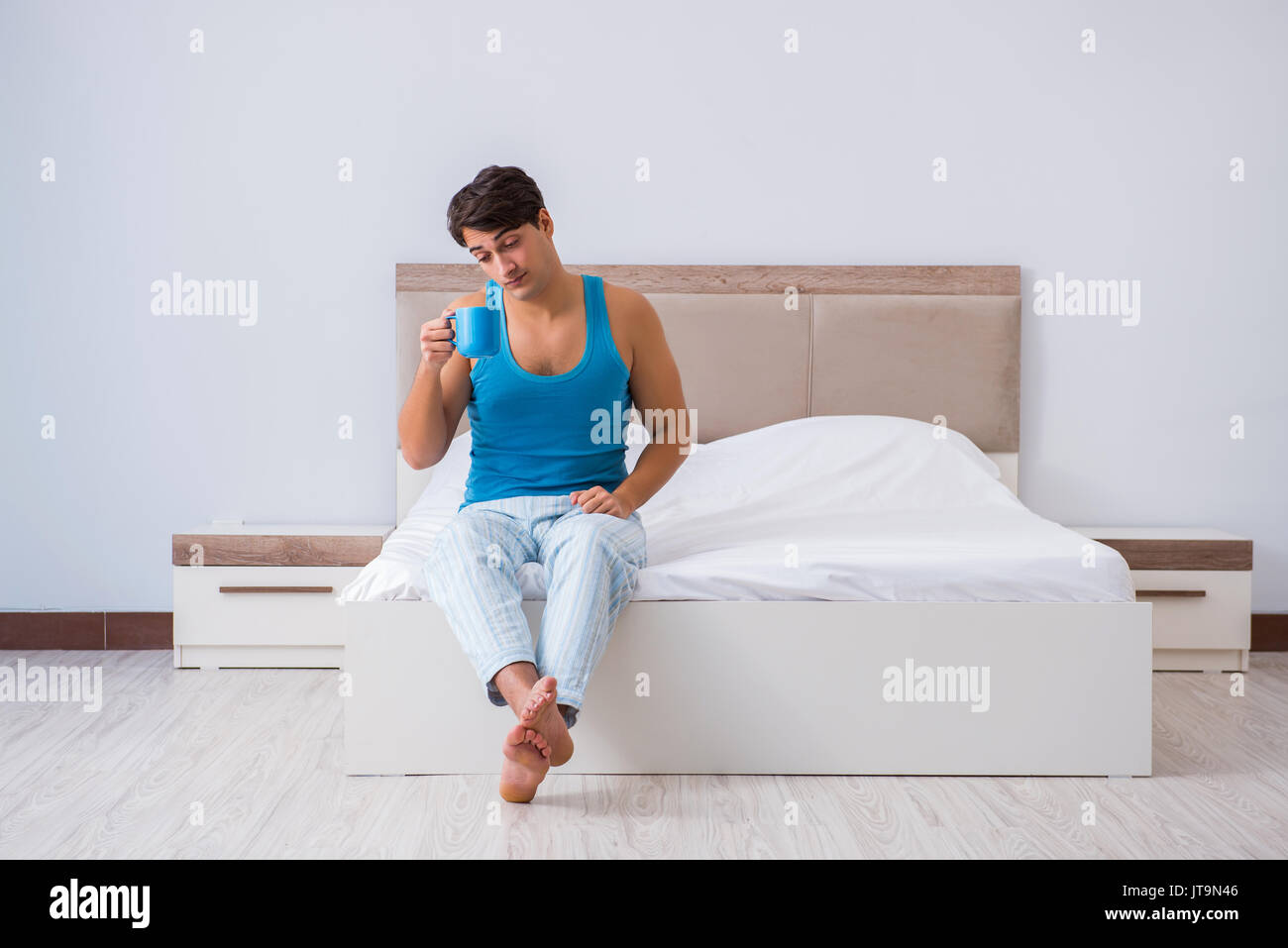 Young man waking up in bed Stock Photo - Alamy