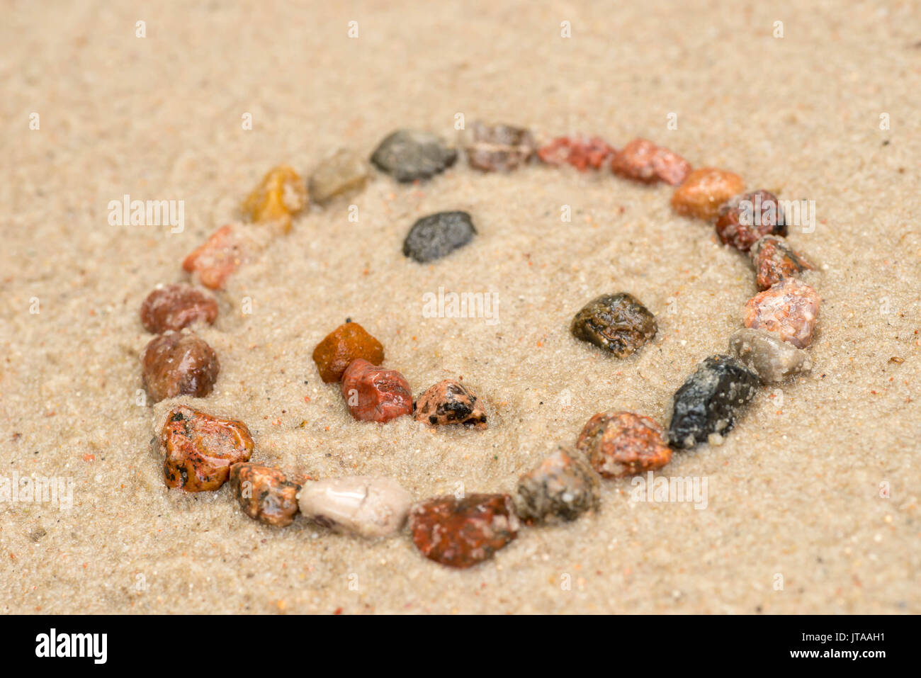 pebble smiling face on sand background selective focus Stock Photo - Alamy