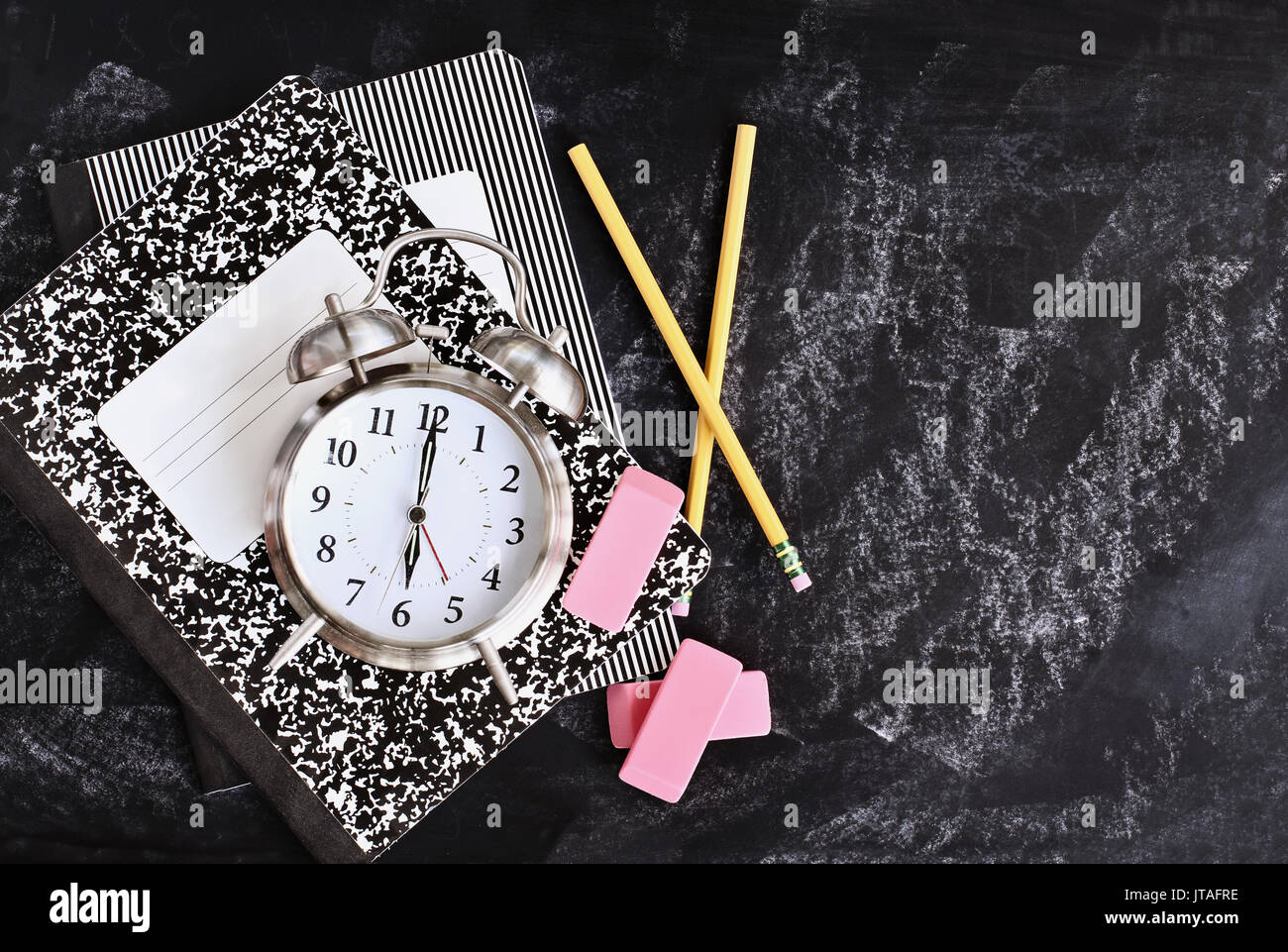 Back to school supplies. Books, alarm clock, erasers and pencils over a ...