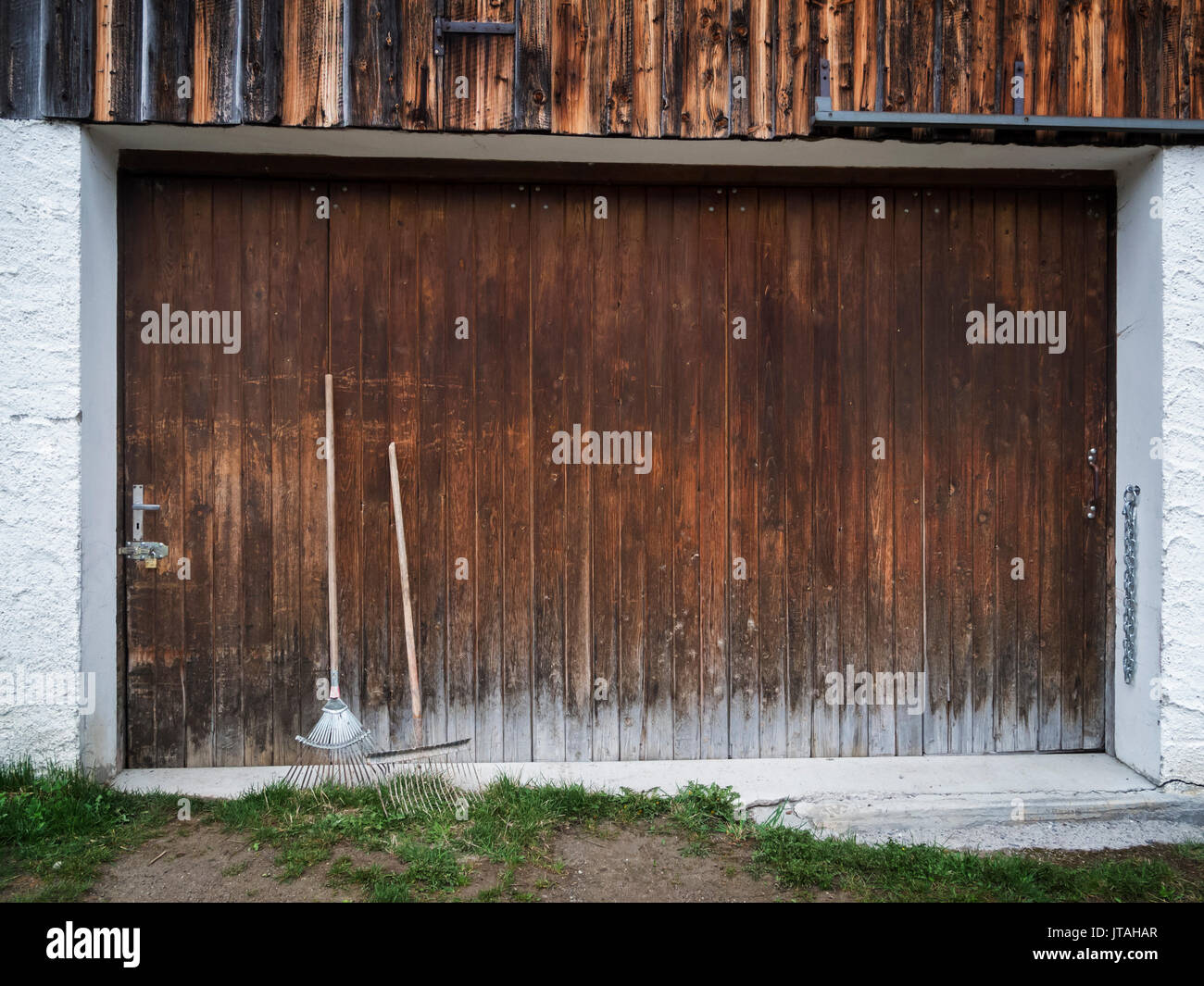 Frontal view of a wide wooden garage gate with two lean rakes Stock ...