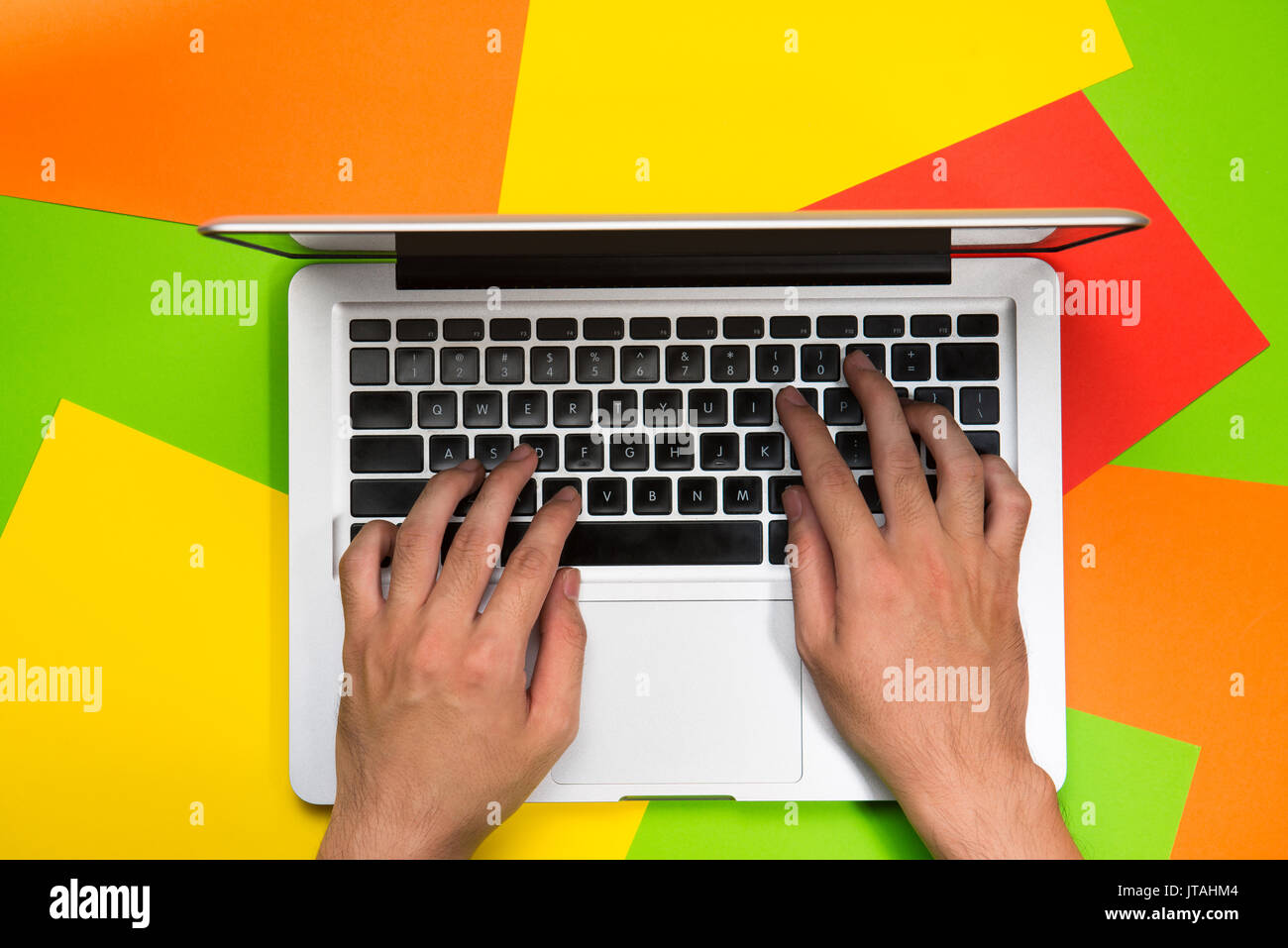Hands typing on laptop on colorful paper. Top view flat lay Stock Photo ...