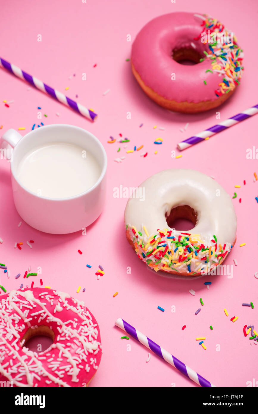 Donuts with icing and milk on pastel pink background. Sweet donuts ...