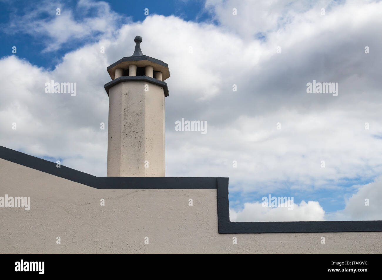 Fence in a matching design with a chimney of a house. Intense clouds on ...