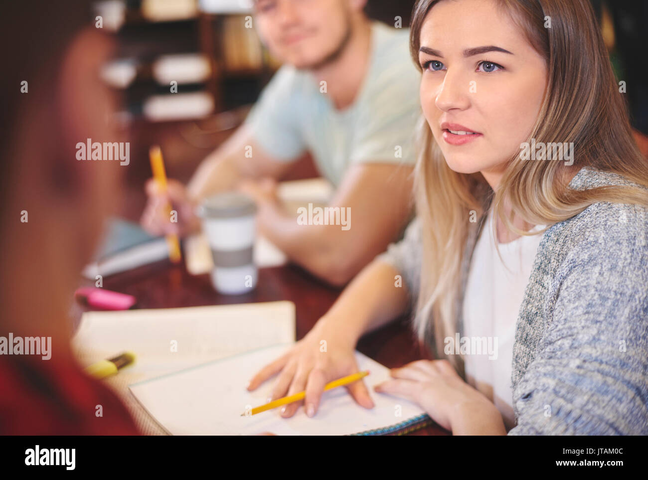 Student writing notes in public library Stock Photo - Alamy