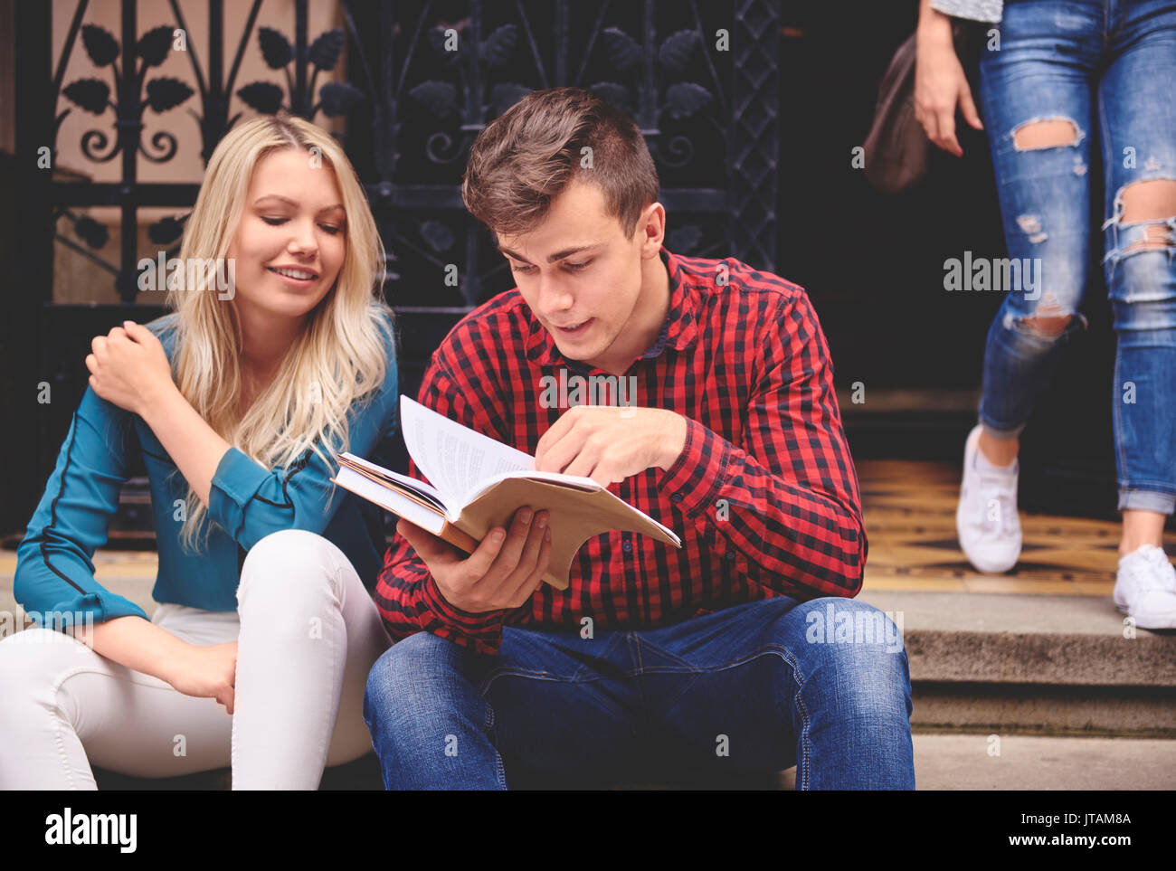 Students studying on stairs with book Stock Photo - Alamy