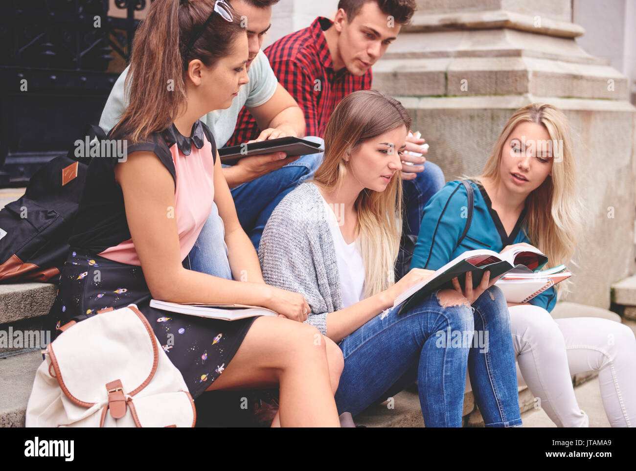 Group of students reading on stairs Stock Photo - Alamy