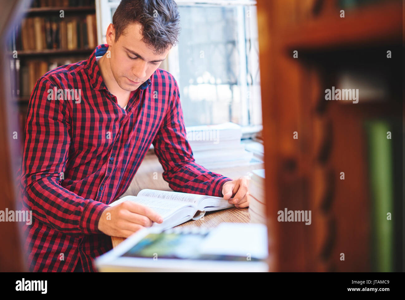 Handsome male student reading a book Stock Photo - Alamy