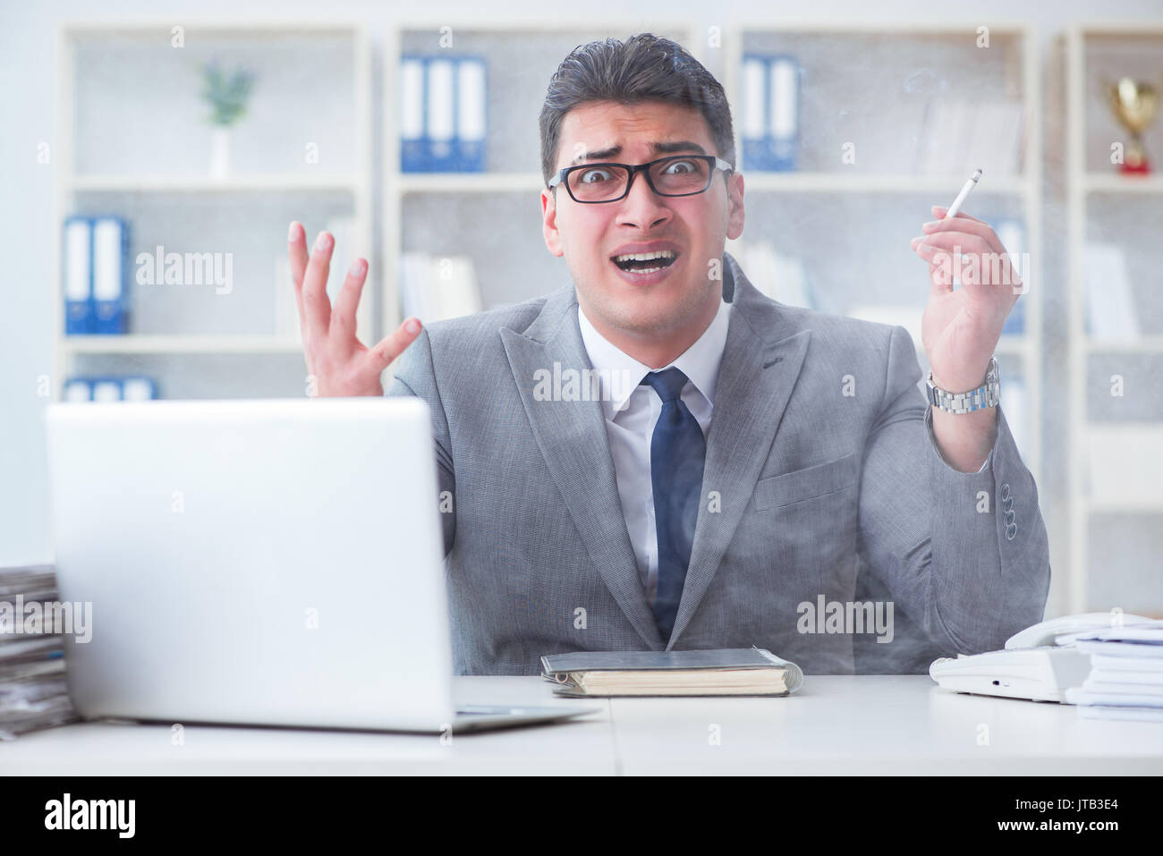 Businessman smoking in office at work Stock Photo - Alamy