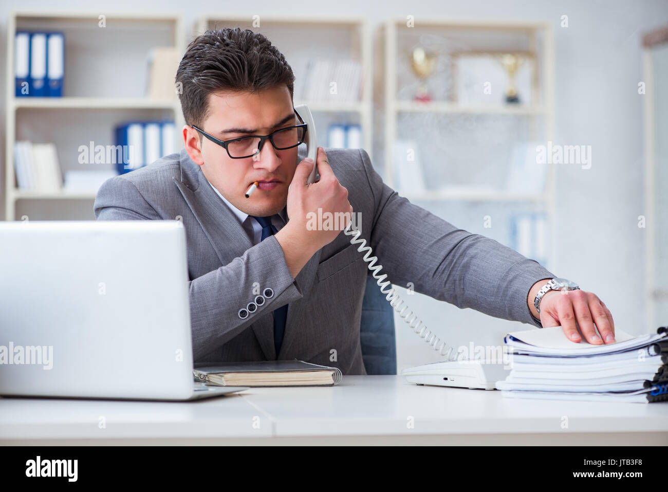 Businessman smoking in office at work Stock Photo - Alamy