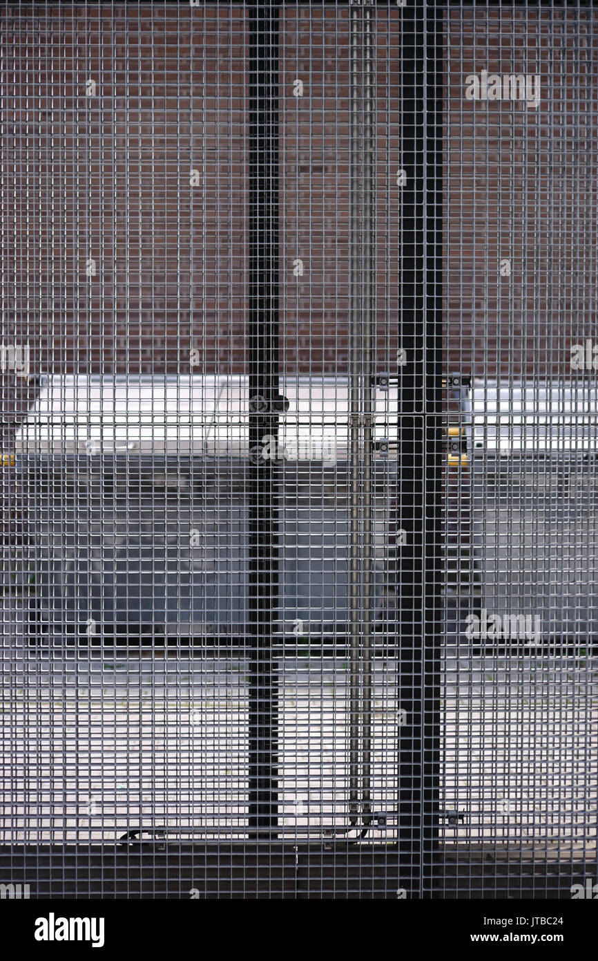 Waste containers are behind a grid fence in a lockable outdoor area ...