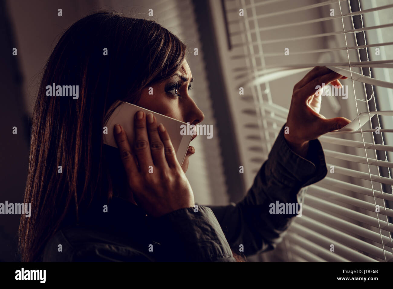 Young abused woman scared looking through the window seeking safety ...