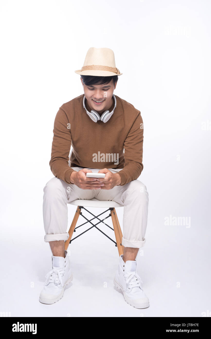 Smart casual asian man seated on chair, in studio background Stock ...
