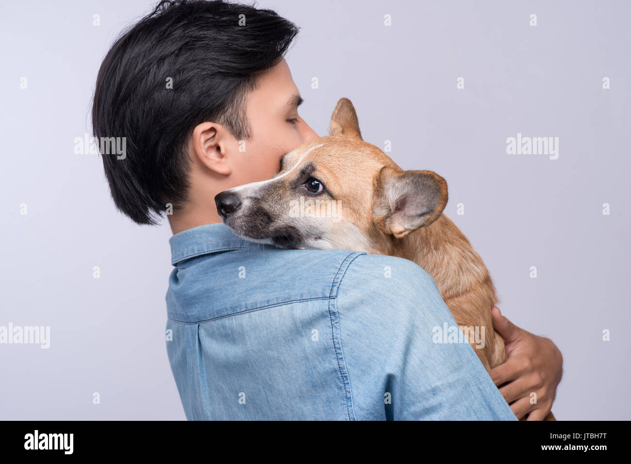 A man snuggling and hugging his dog, close friendship loving in studio ...