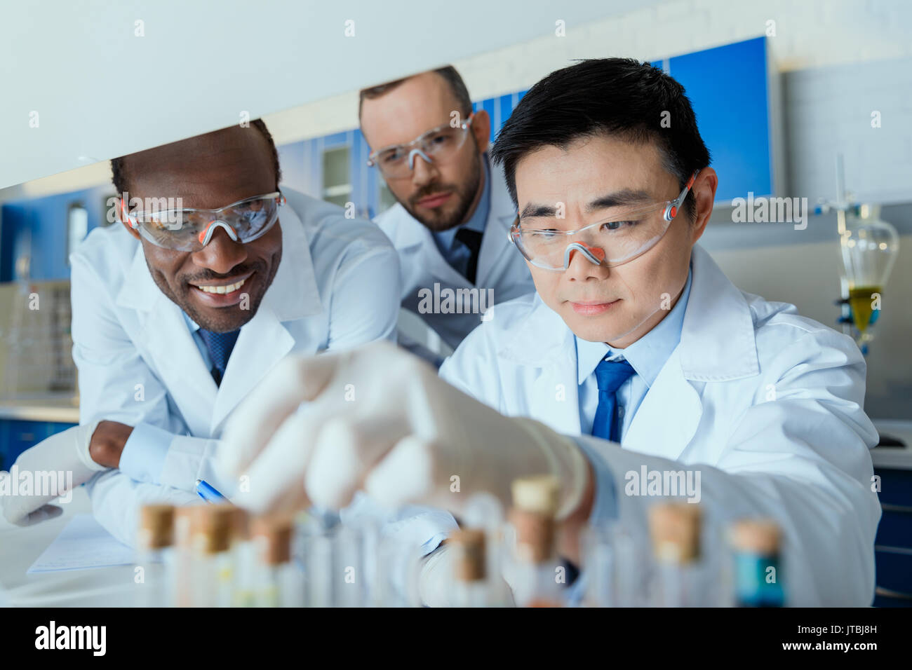 Multiethnic group of scientists in protective eyeglasses working ...