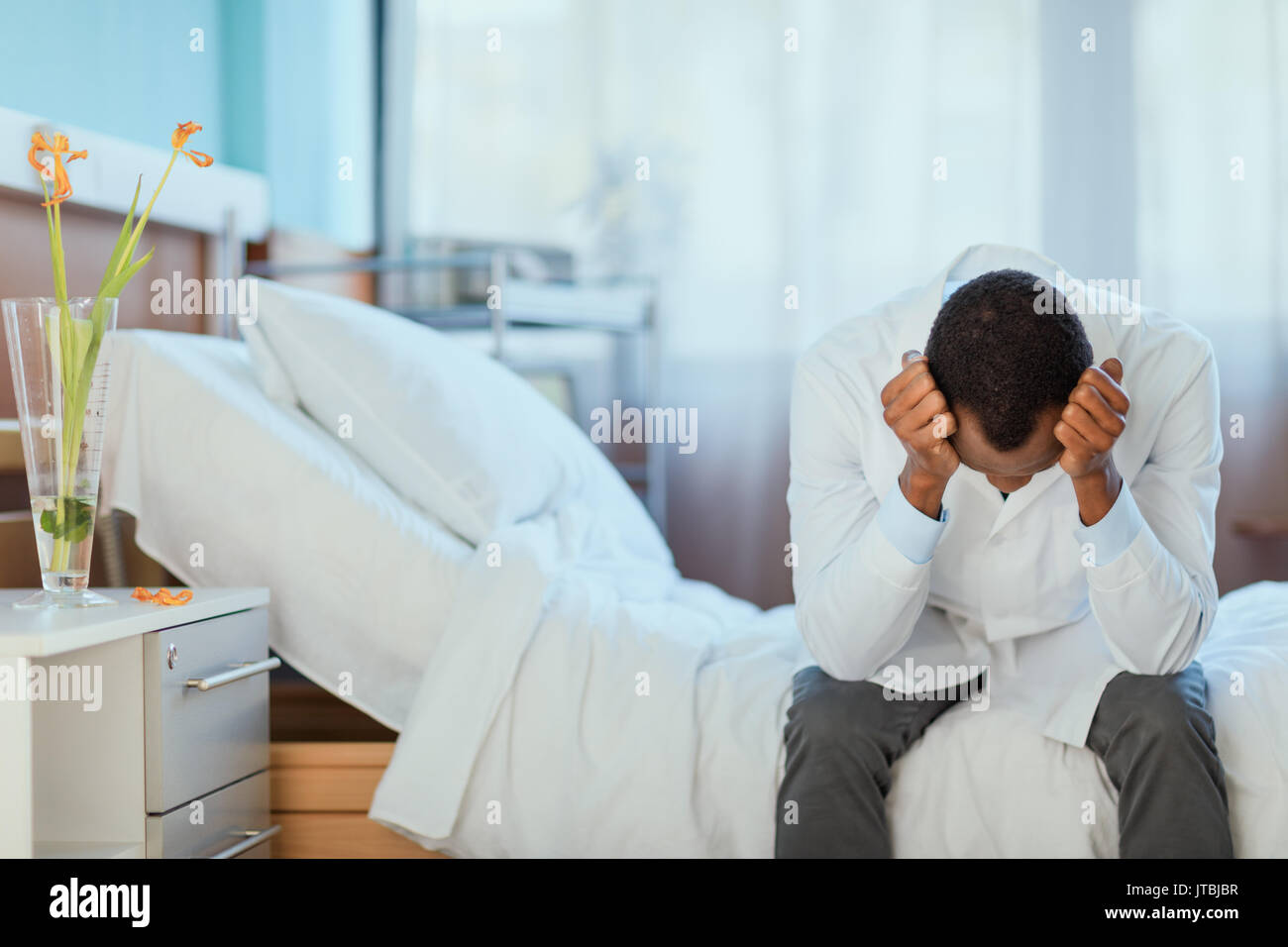 front view of upset doctor sitting on bed in hospital chamber Stock ...