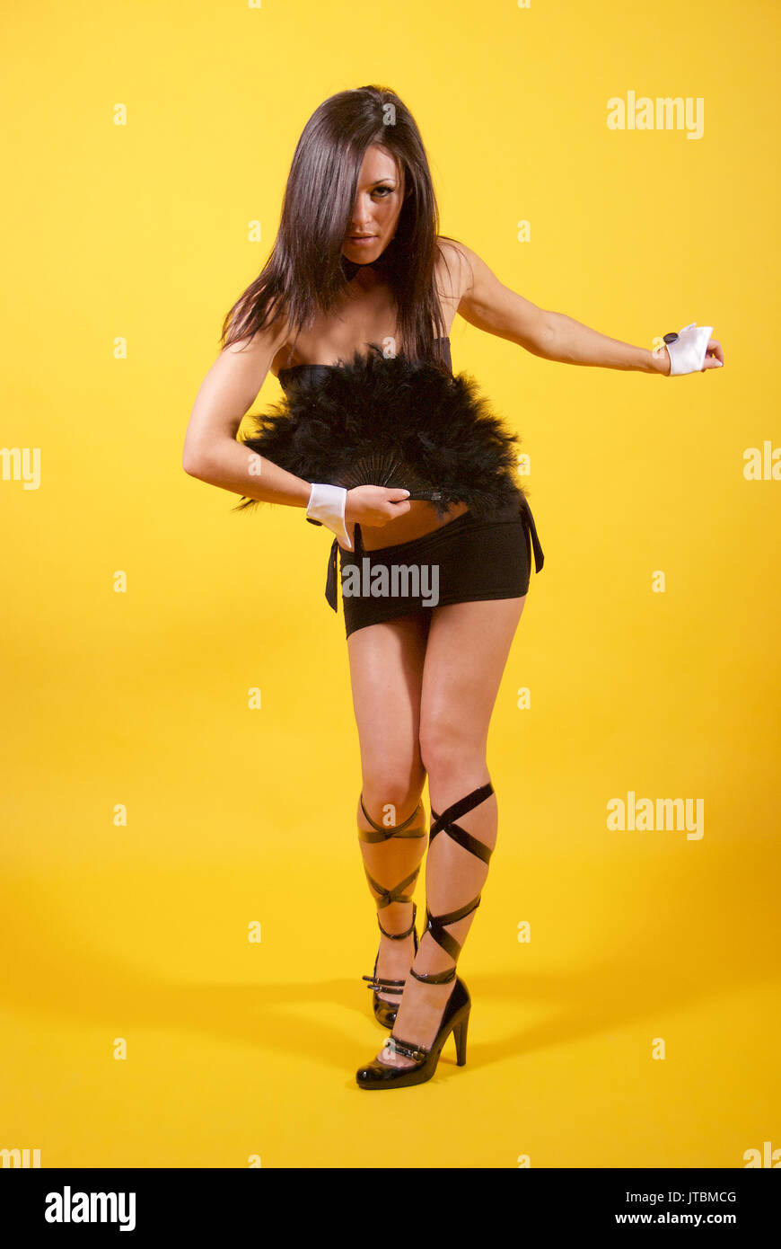 Beautiful brunette girl dancer in the studio with a yellow background ...