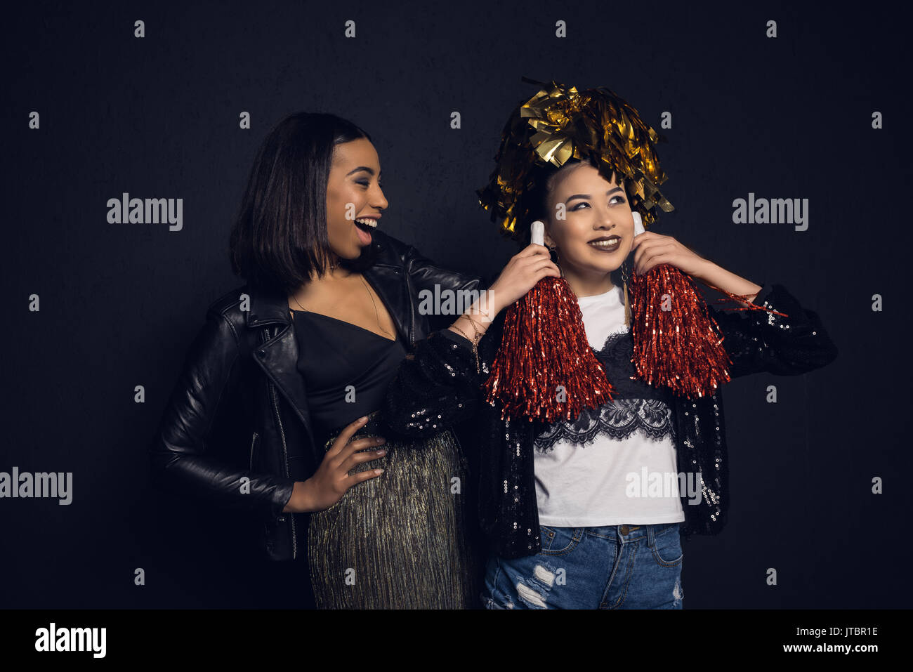 Beautiful smiling young women having fun with shiny pom-poms isolated ...