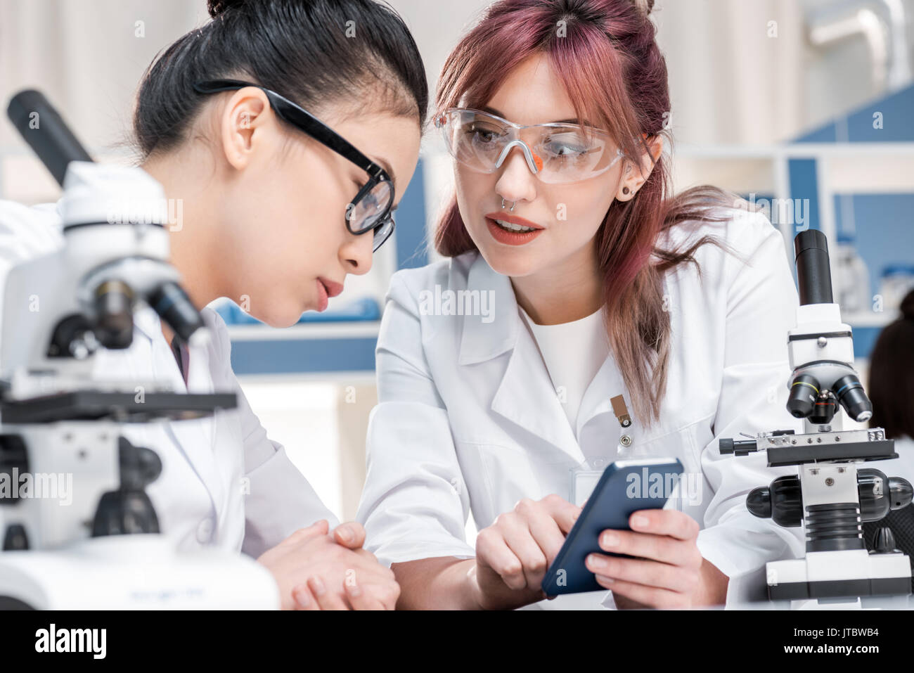 scientists working together with microscopes and smartphone in chemical lab, scientists team ...