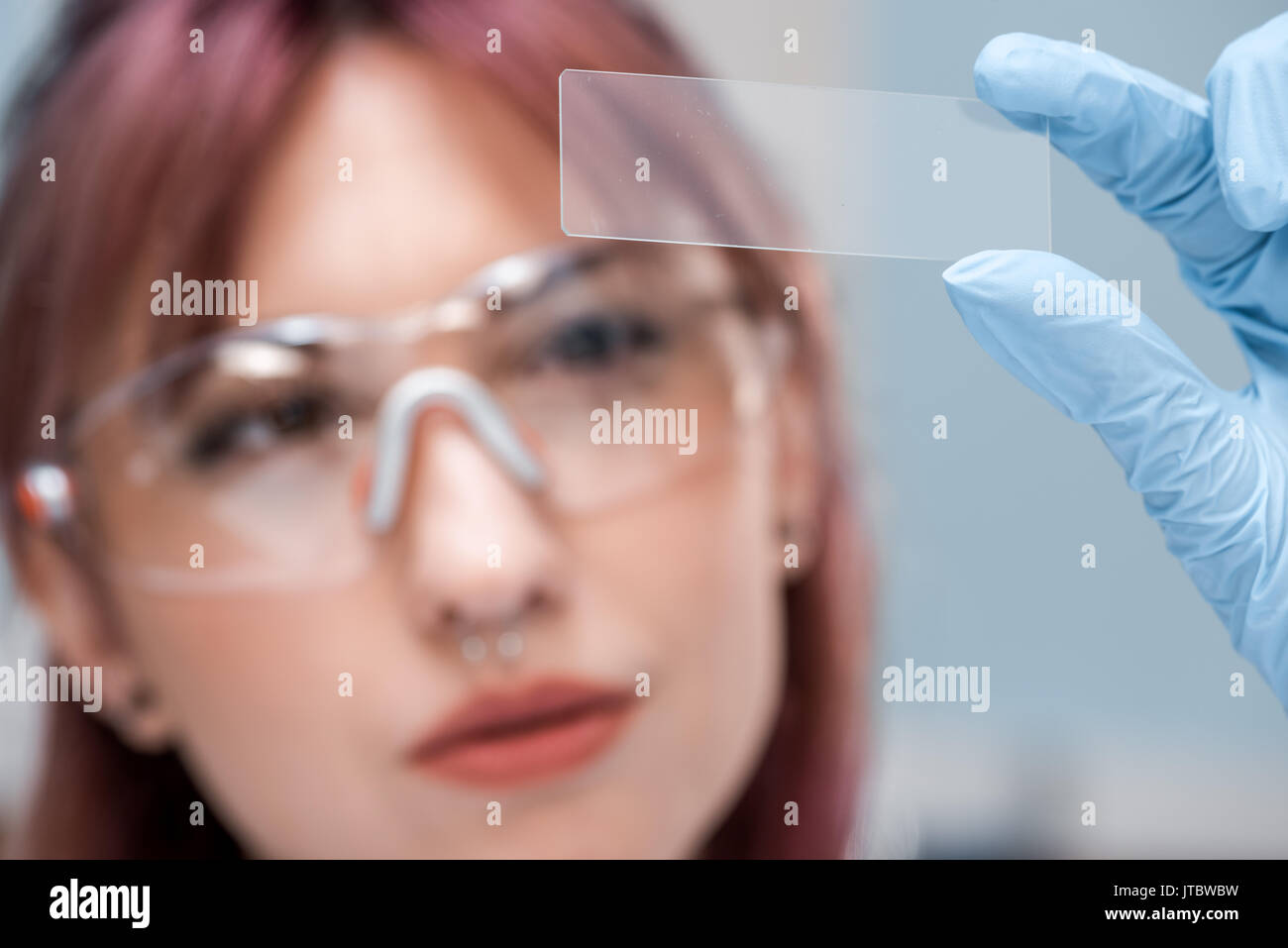 Close-up view of concentrated young scientist in eyeglasses holding ...
