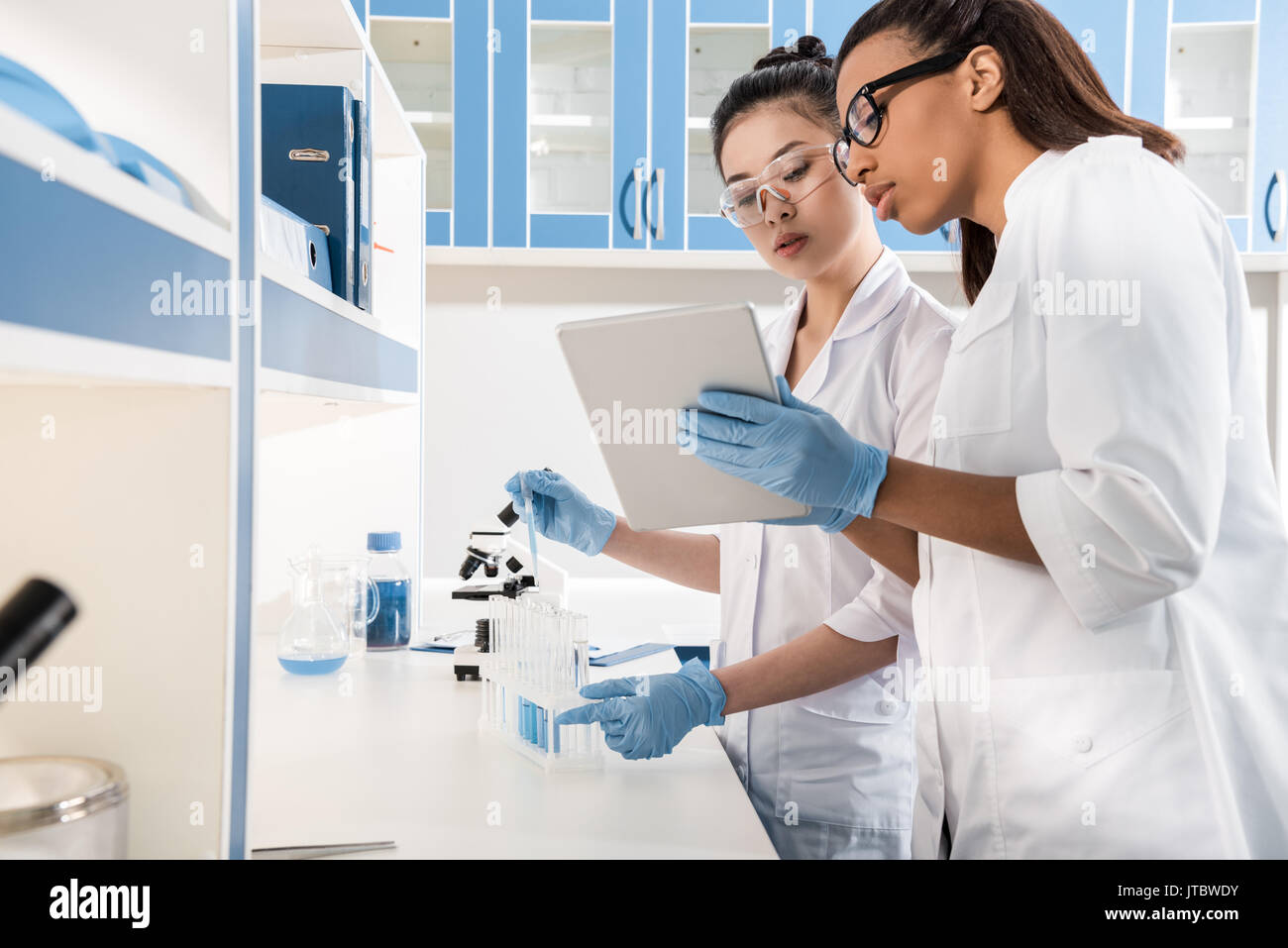 Professional young scientists using digital tablet while making ... Professional young scientists using digital tablet while making ...